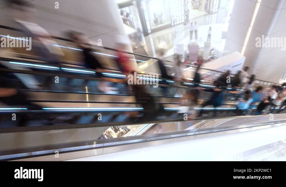 Shopping mall busy scene. People on escalator move fast with blurred ...