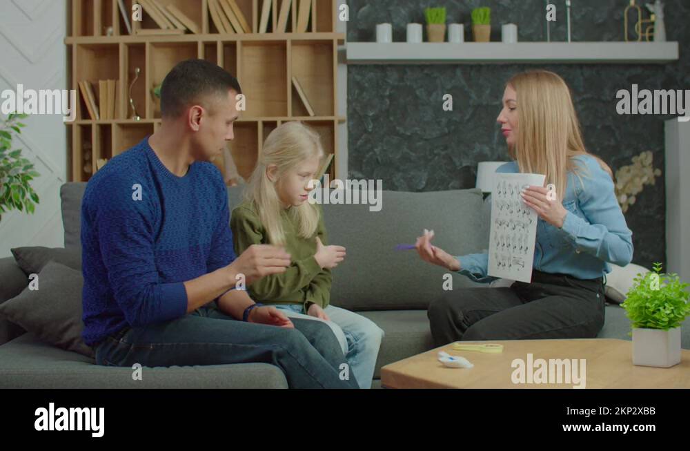 School age girl with hearing loss and parents learning English sign ...