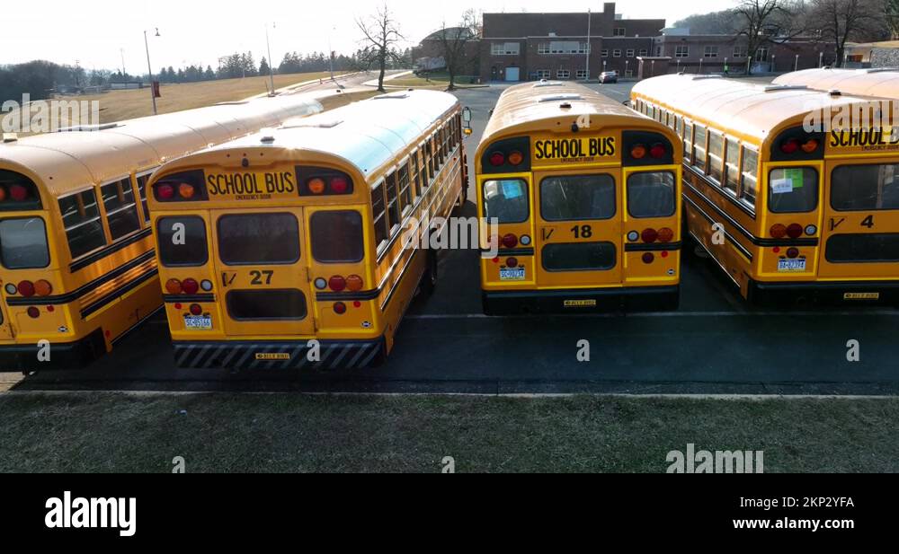 School bus line up. Rising aerial reveals public school building in USA ...