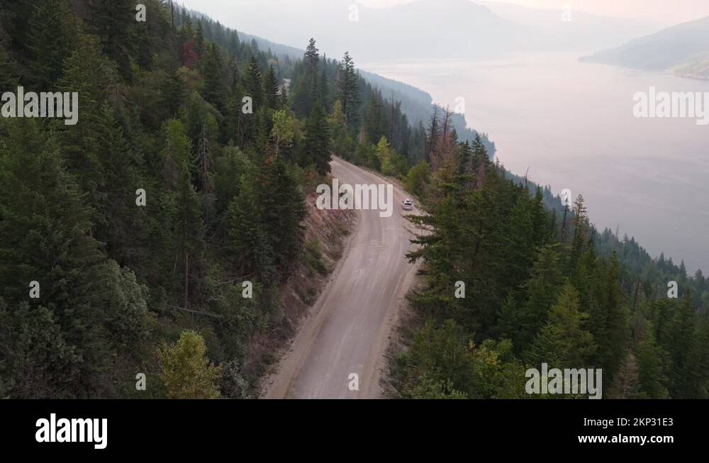 Silver van driving along a dusty forest service road in Canada during ...