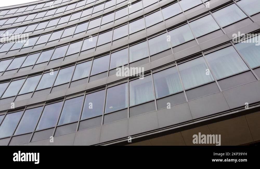 Low angle viewpoint upwards many office windows on curved city building ...