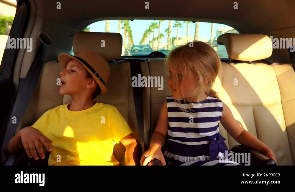 Boy and girl are riding in the backseat of the car and looking at the ...