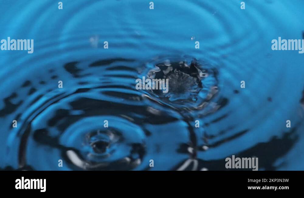 Slow motion. Two drops falling into blue water. Rain drops falling on ...