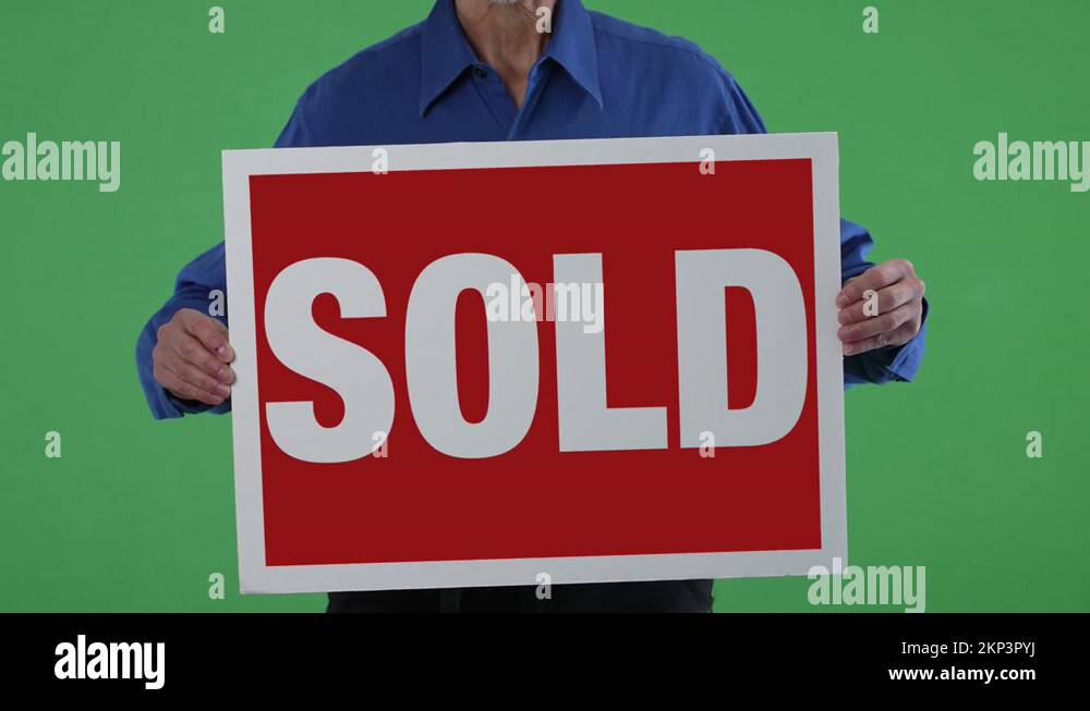 Real estate agent holding SOLD sign on green screen chroma key ...