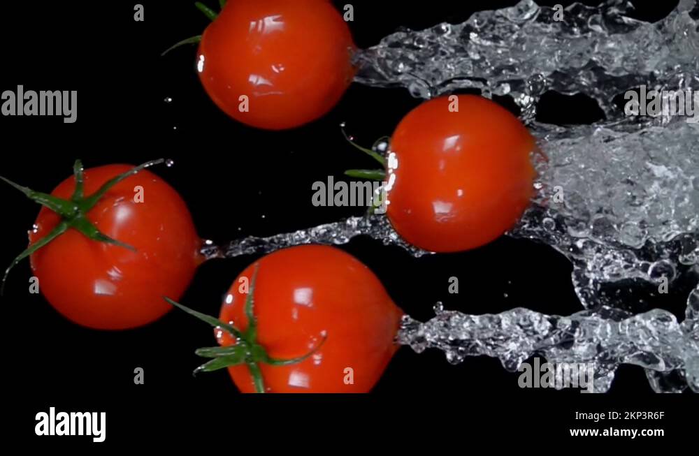 Small cherry tomatoes are bouncing horizontally on the black background ...