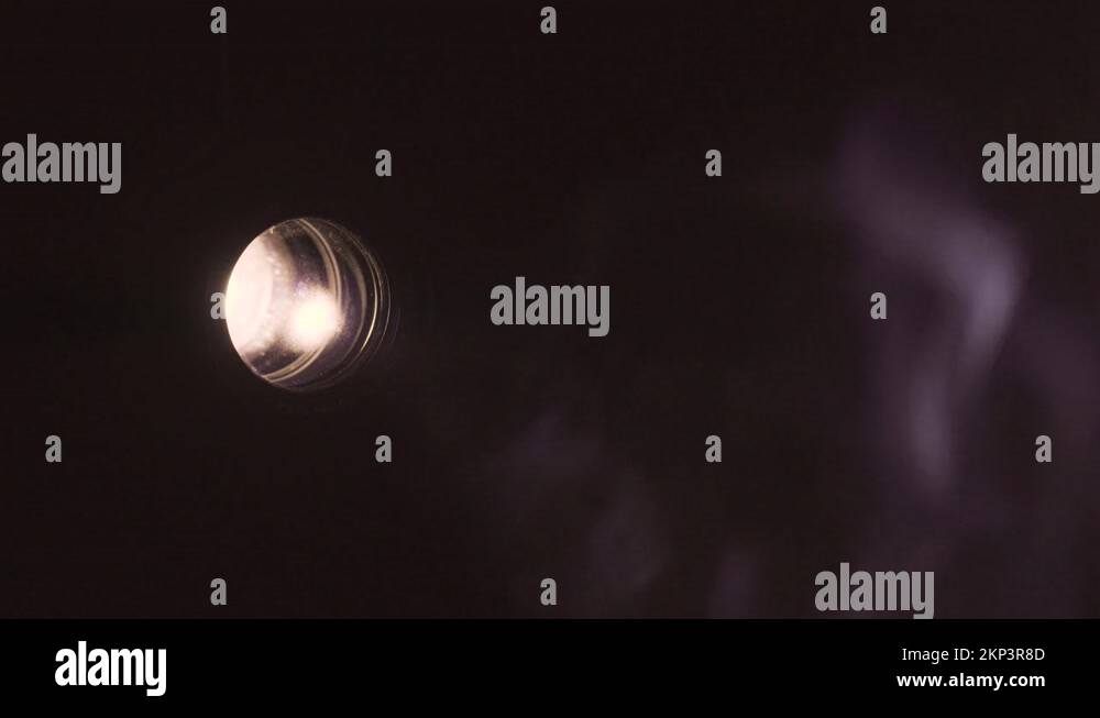 Cine camera projector light beam with smokey fog backlit in dark room ...