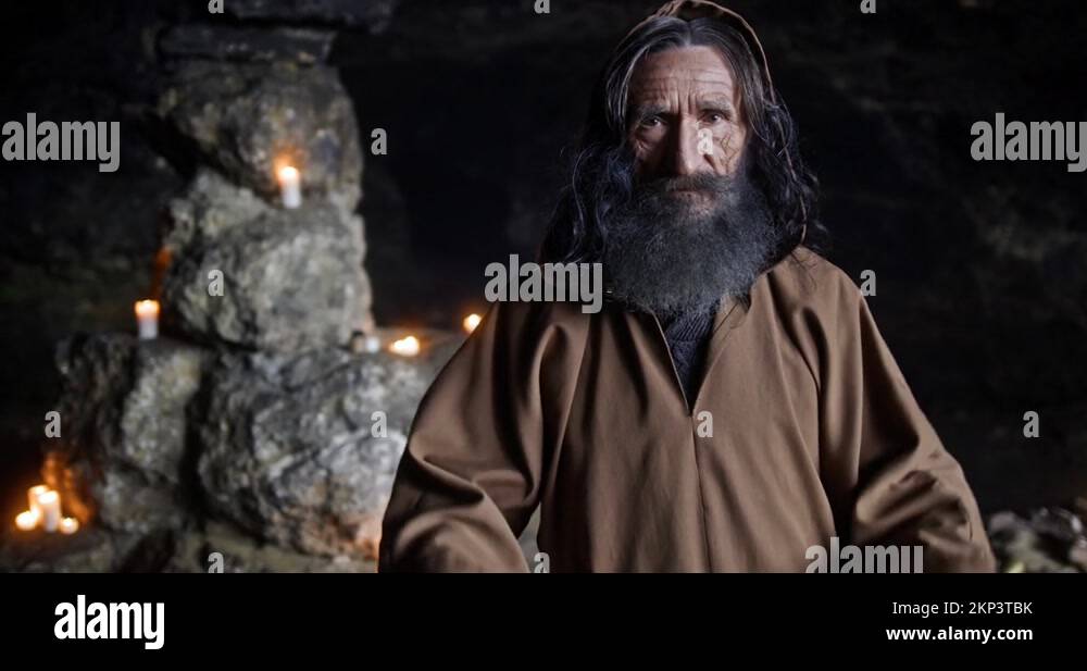 Portrait of a medieval bearded monk taking off the hood of his robe ...
