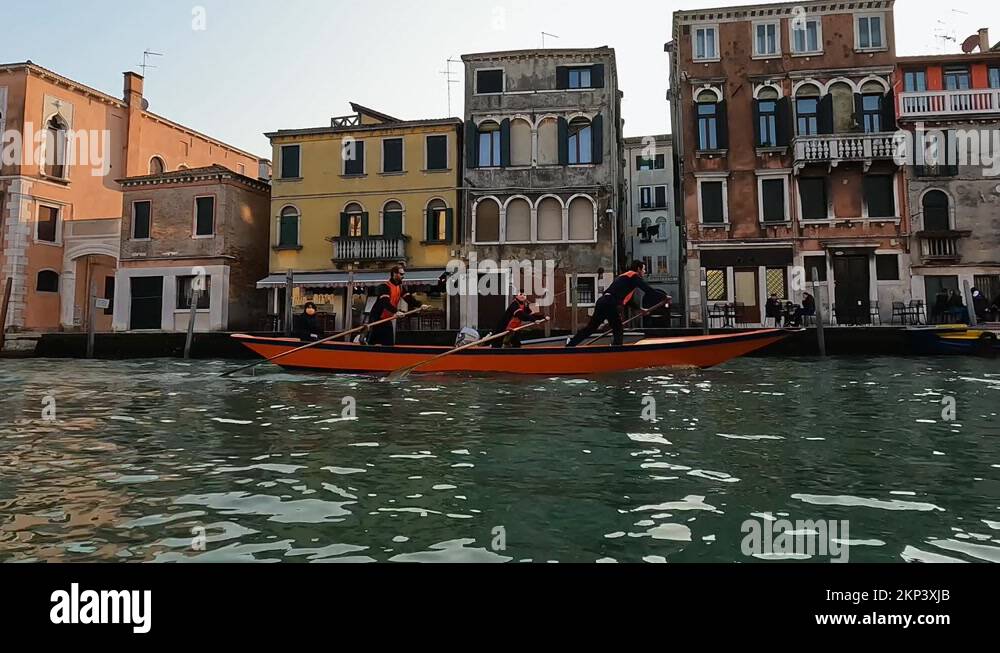 Team of four rowers training rowing standing on Venetian canal of ...