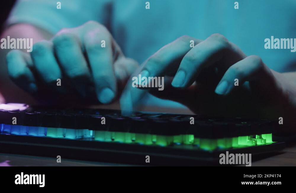 Gamer typing on backlight keyboard close-up, man playing video game ...