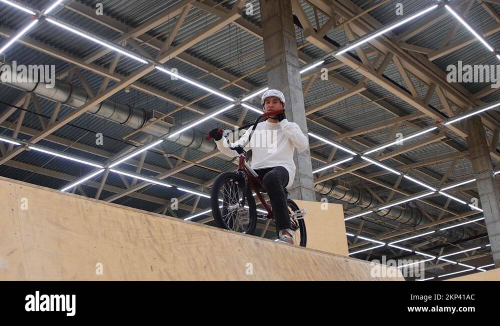 BMX sports - young man riding on the top of the springboard and takes ...