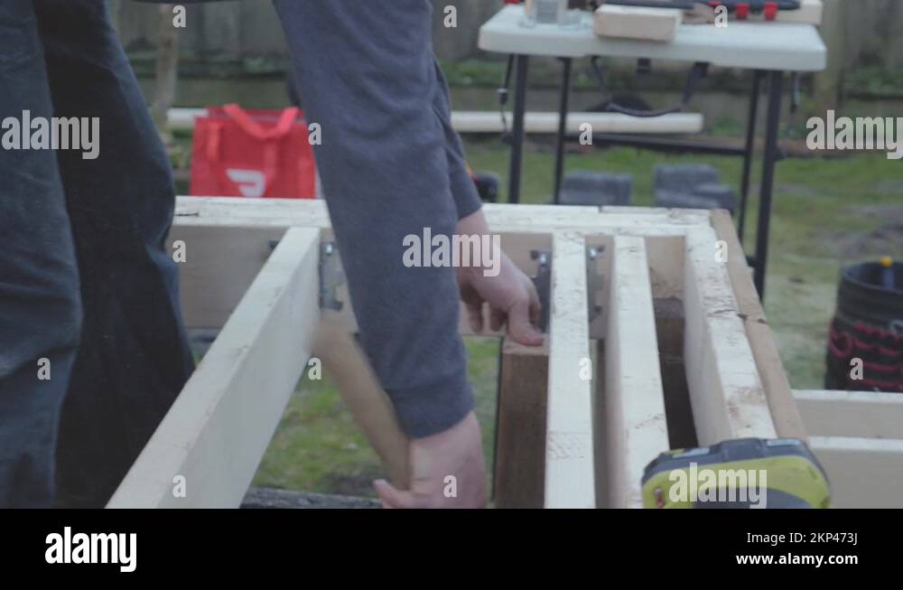 carpenter using hammer to adjust wooden support holding up frame to a ...