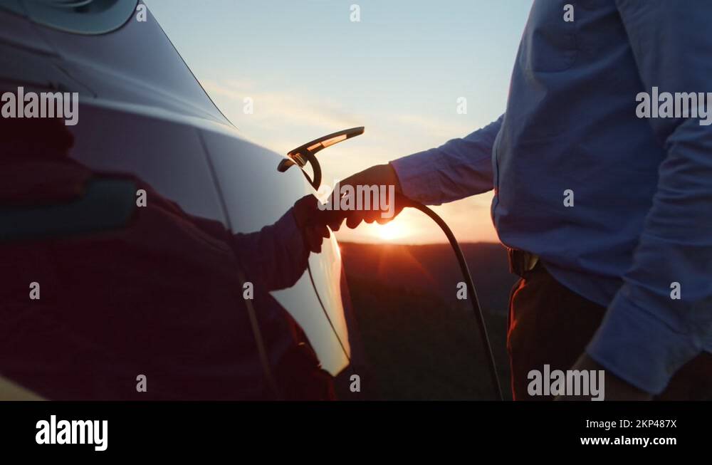Male hand inserts power connector into EV car, man plugging in charging ...