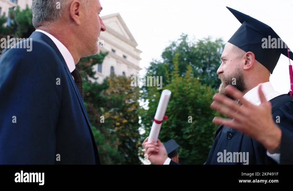 Good looking man graduate have a conversation with his dad after the ...