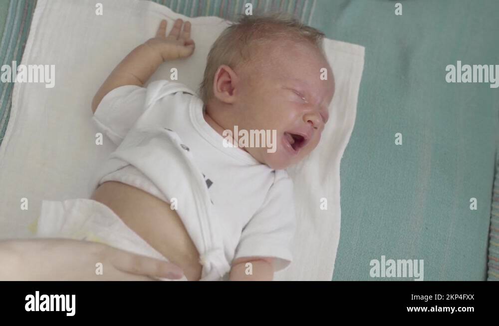 Toddler girl crying on a bed. Changing diapers of a newborn baby Stock ...
