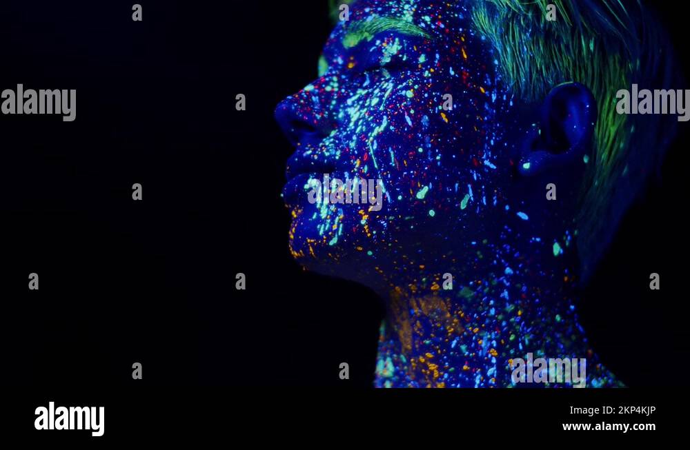 Man face painted with fluorescent colors in profile, turns head and ...