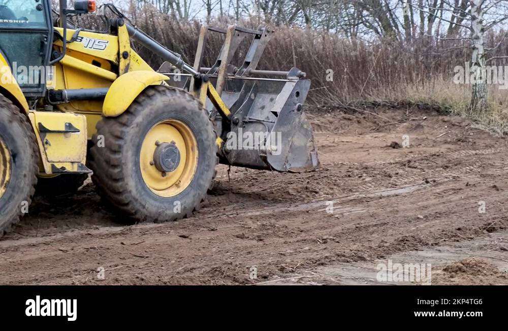 Tractor levels field. Backhoe loader clearing construction site ...