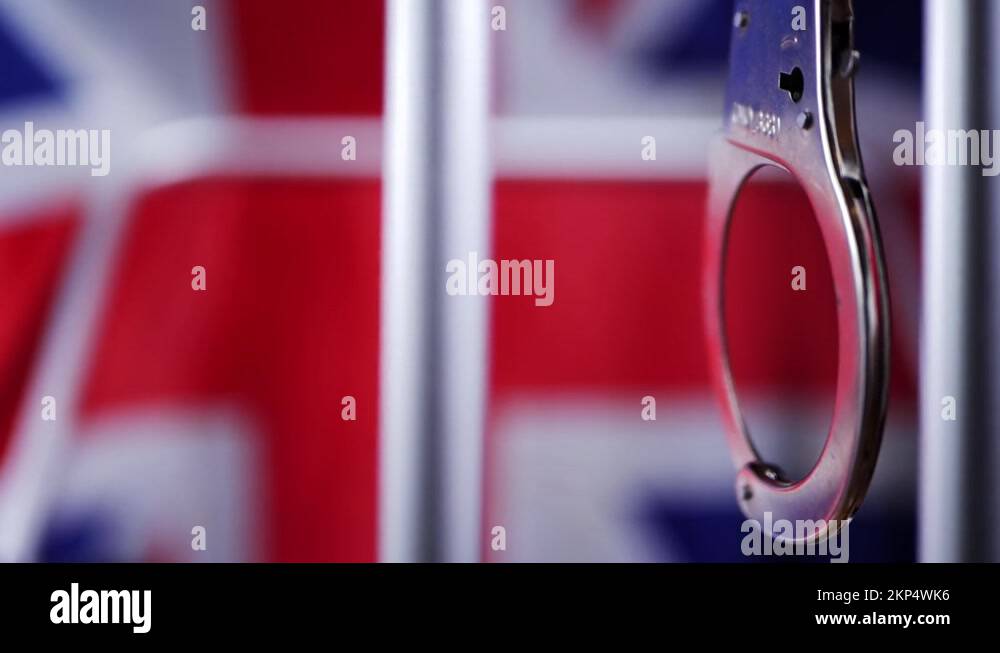 Handcuffs swing on prison bars with Union jack British flag background ...