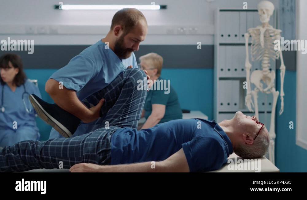 Male osteopath cracking legs bones and helping old man with muscles ...