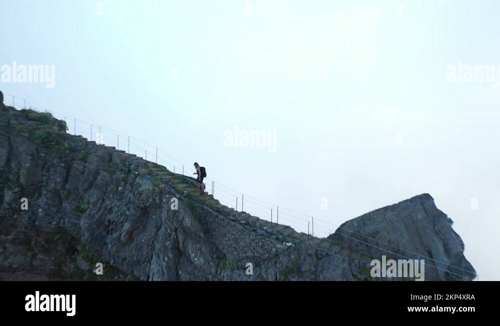 Young man walking up the stairs on the ridge of Pico das Torres in ...