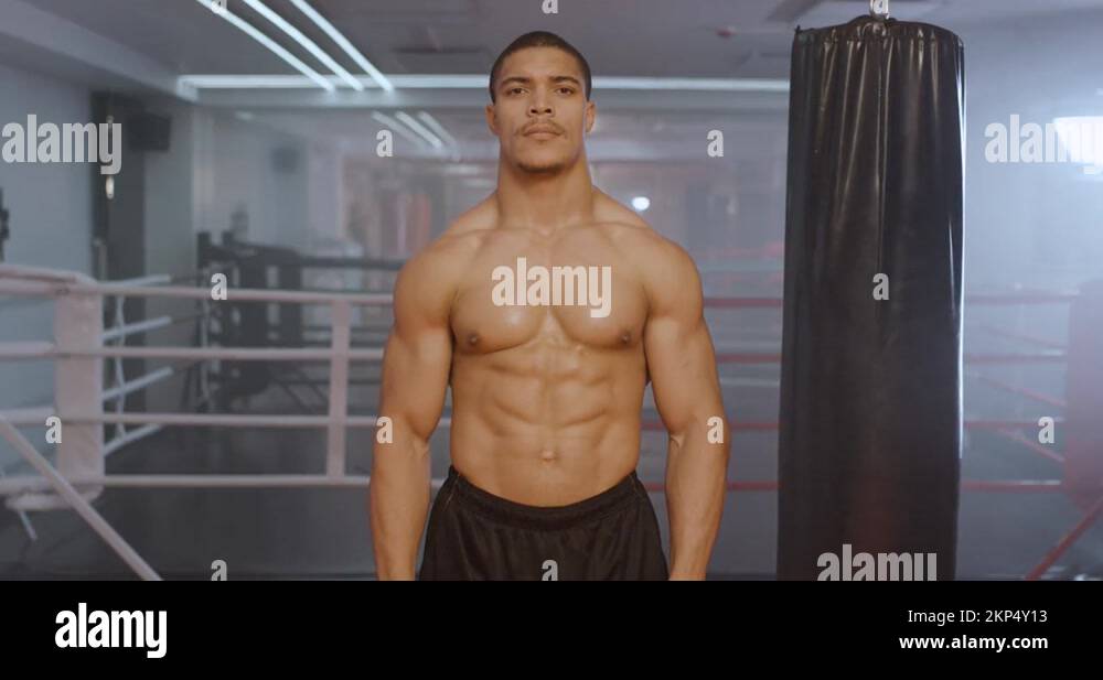 Athletic man fighter trains in boxing gym, a muscular male takes a ...