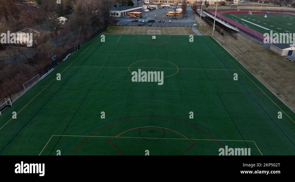 School athletic field and campus. Aerial tilt up reveals school ...
