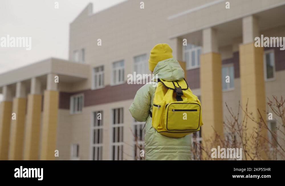 little girl with satchel goes to lesson in school building. childhood ...