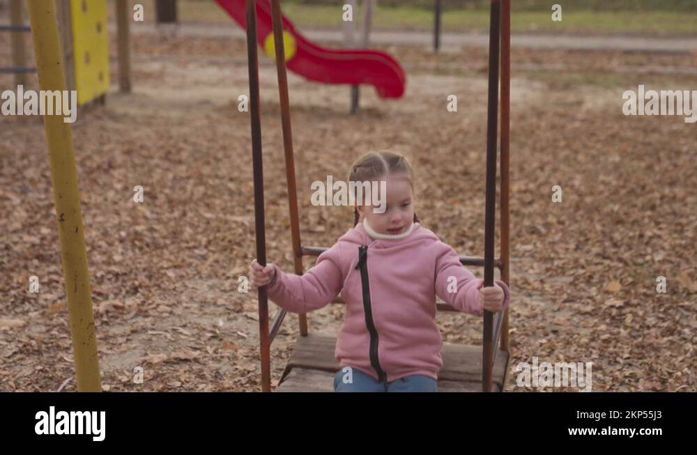 little girl swinging on swing autumn park, child with her mother is ...