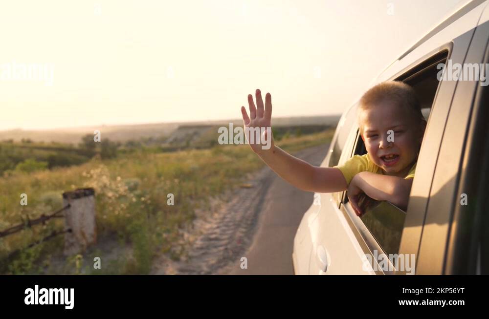 Teen looking out car window and waving his hand. Family travel by car ...
