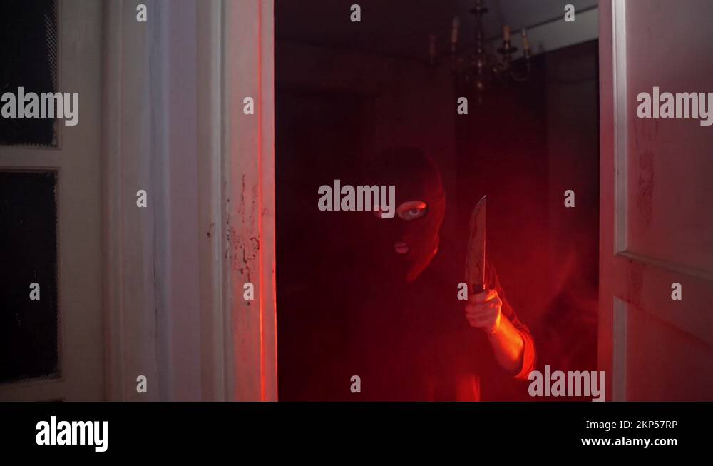 Serial killer in balaclava mask haunting his victim with bloody knife ...