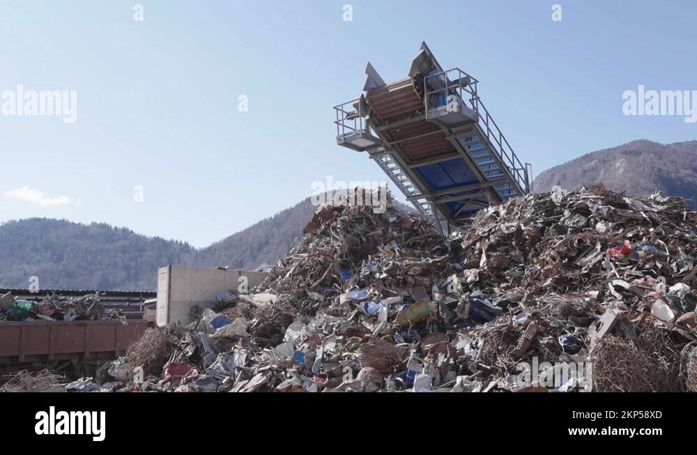 Crushed recycling steel pieces falling from conveyor belt to big pile ...