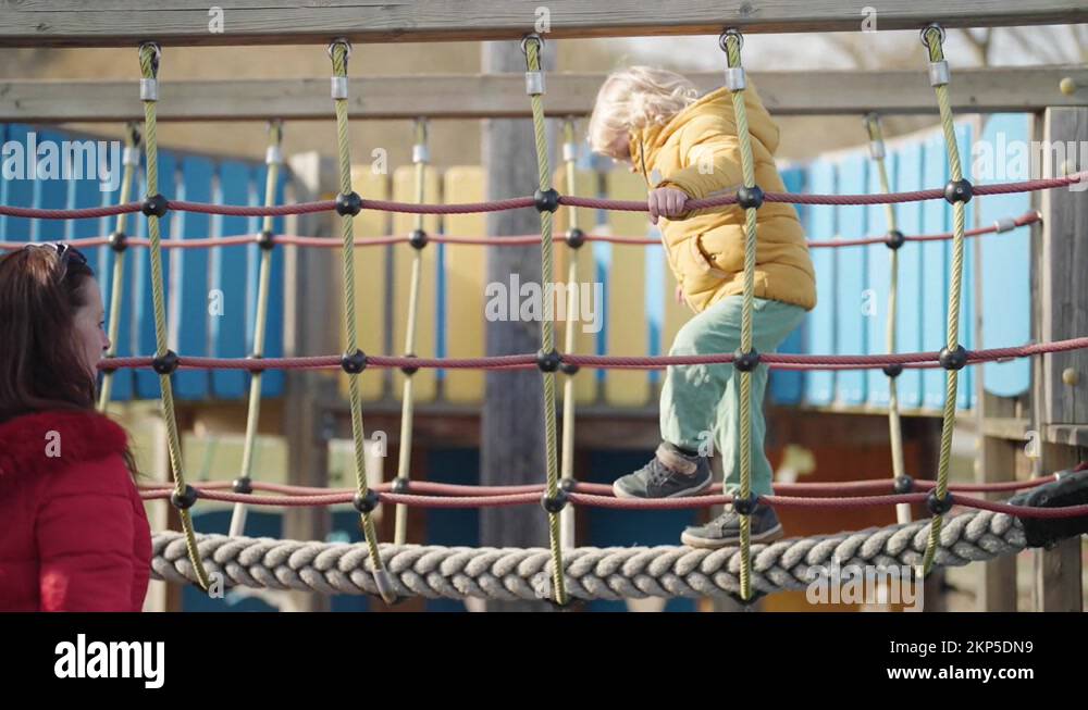 Child carefully walk over rope bridge on playground castle 4K Stock ...
