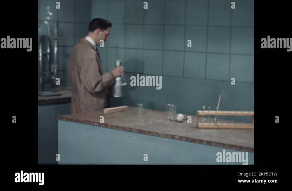1940s: Lab equipment on table, man enters with tank, pours liquid from ...