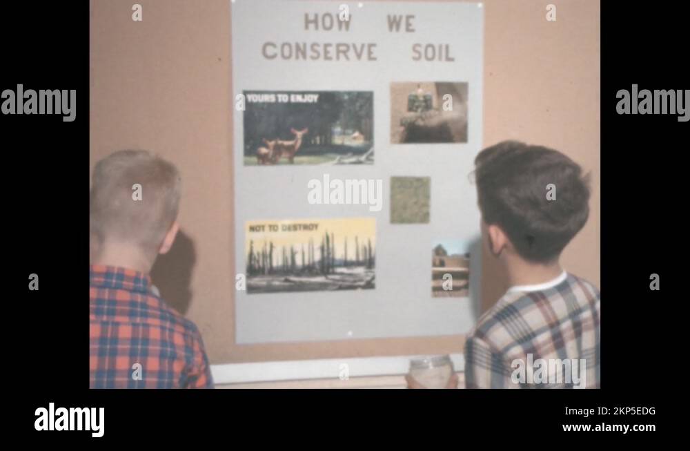 1960s: Two boys holding jars of water discussing poster for soil ... 1960s: Two boys holding jars of water discussing poster for soil ...