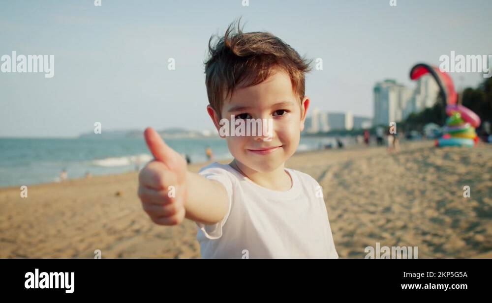 Cute child shows thumbs up gesture, happy facial expression emotion ...