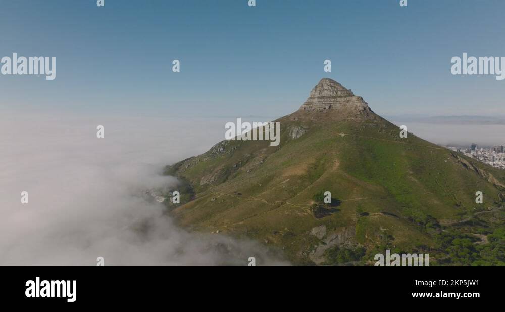 Lions head mountain rising from fog. Aerial descending shot of steep ...