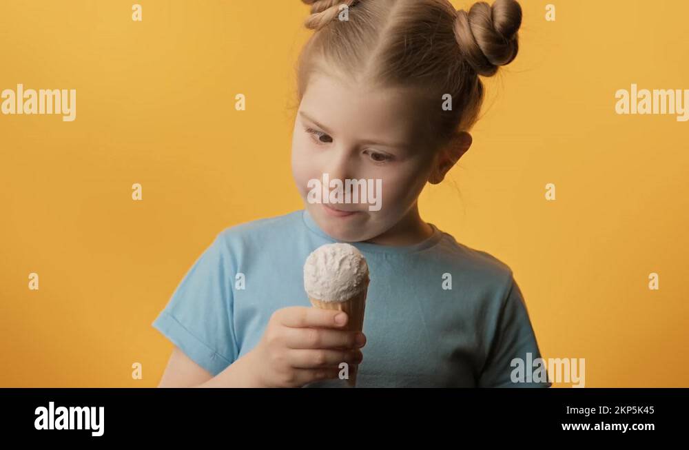 Toothless girl eating ice cream cone on yellow background. Cute little ...