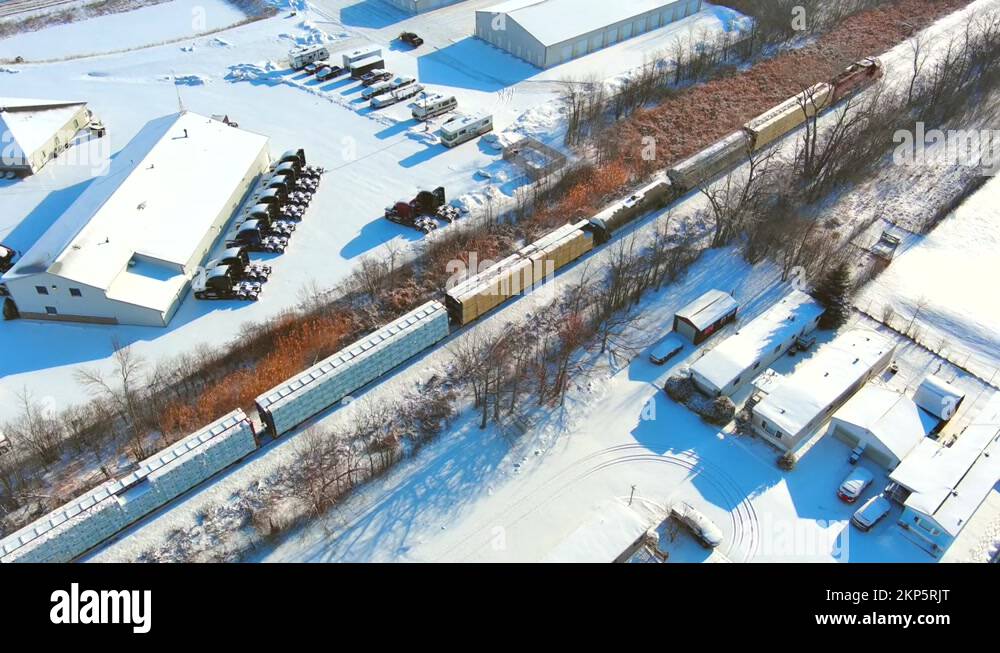 Freight train covered in fresh snow rolls across snow-covered landscape ...