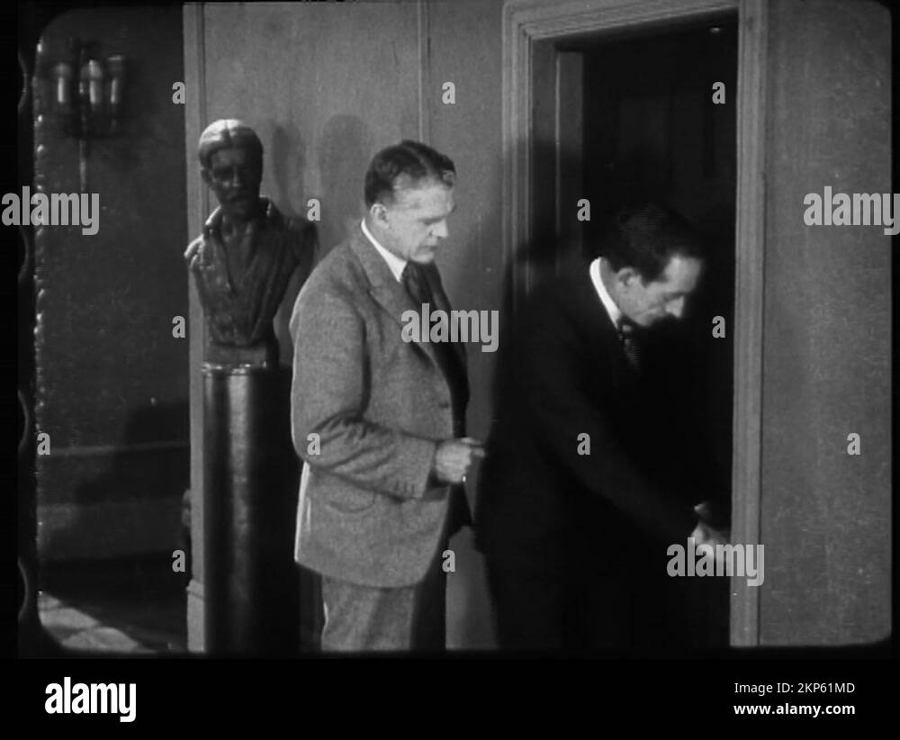 Two men exiting room and meeting scared man in hall, United Kingdom ...