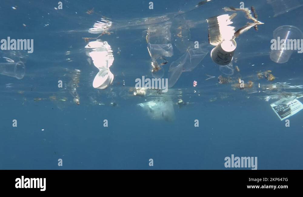 large plastic trash swim in the blue water under surface. Underwater ...