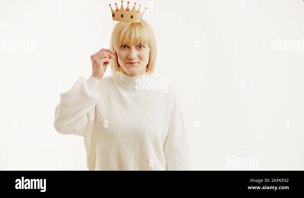 Amused young woman with fake crown on a party on white background ...