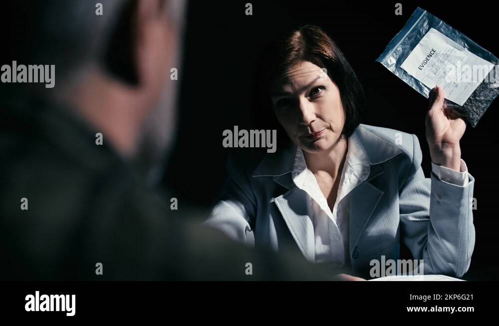 Female police detective showing evidence bag to suspect in custody ...