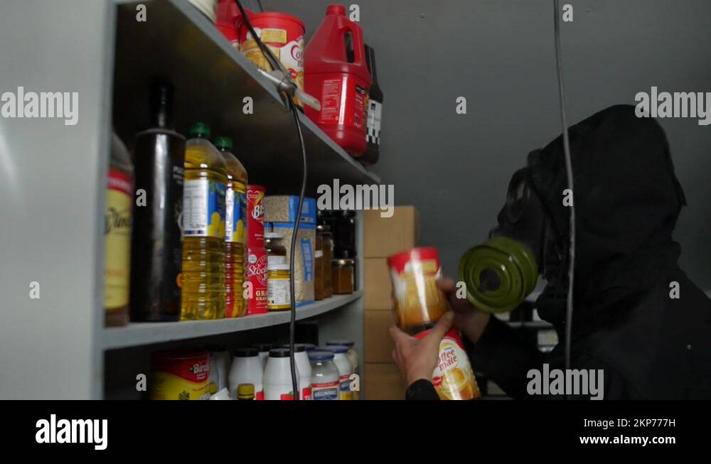 A prepper wearing a gas mask in a nuclear fallout bunker stockpiling ...