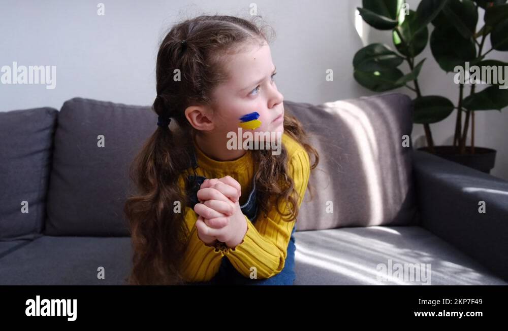 Hopeful little girl kid keep hands in prayer hope sitting on sofa at ...