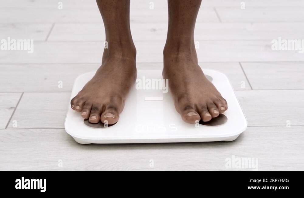 Legs of black girl standing on scale to measure weight. African ...