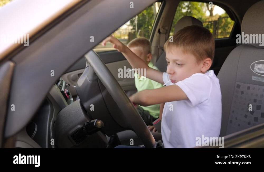 Two boys are sitting behind the wheel of a car and pretending to drive ...