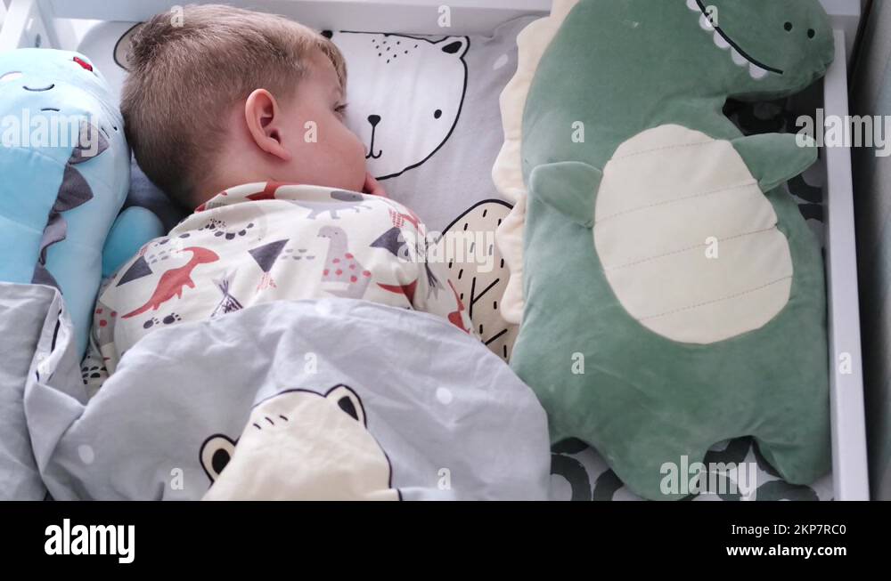 A cute little boy is sleeping in his crib, the baby is awake and ...