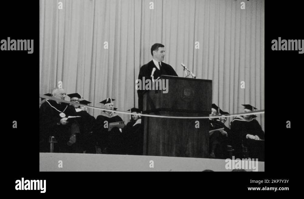 1960s: People sit on stage in caps and gowns, man stands at podium with ...