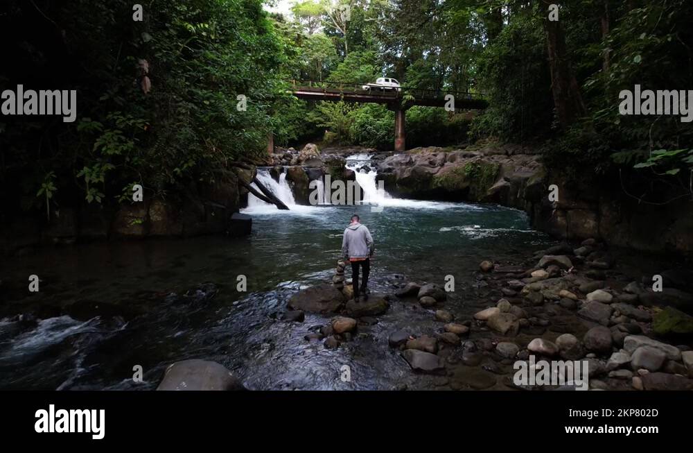 Man jumping rocks in tropical river banks in Costa Rica's jungle ...