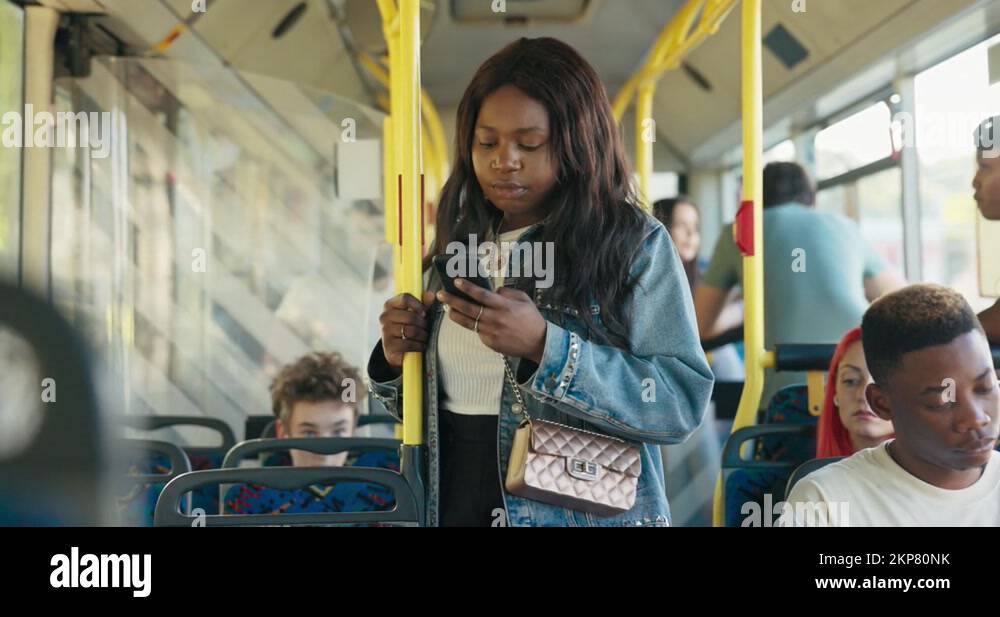 An attractive woman rides in a public transport bus holding on to a ...