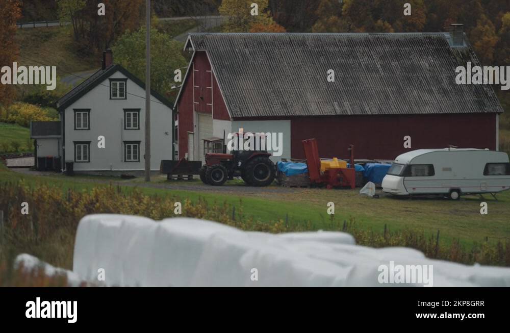 A farmhouse and a barn in rural Scandinavia. A tractor and a caravan ...
